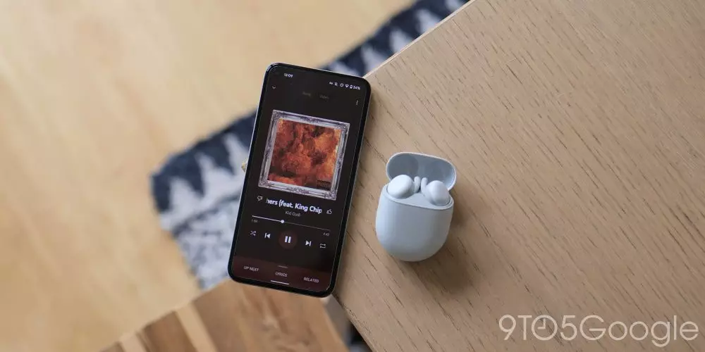 Clustffonau cyfres A Google Pixel Buds mewn gwyn ochr yn ochr â'r Pixel 5 yn chwarae Kid Cudi ar YouTube Music ar gyfer Android.